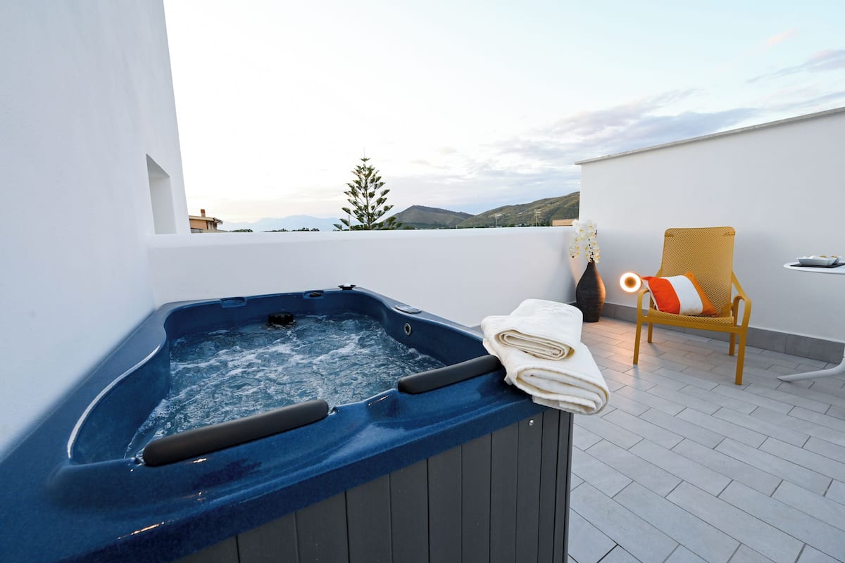 Terraço no telhado com banheira de hidromassagem, uma cadeira com almofada e uma toalha.