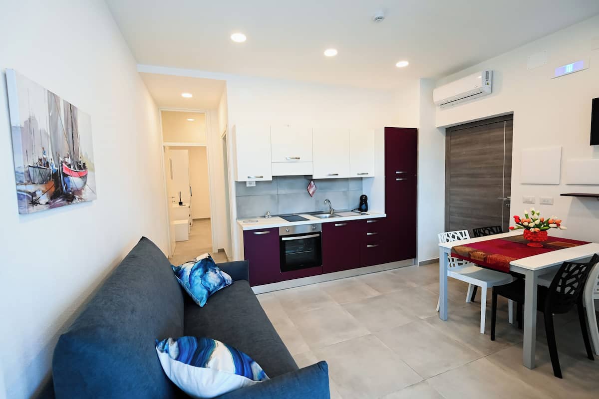 Uma cozinha moderna com armários brancos, forno embutido e uma área de jantar com mesa e cadeiras.
