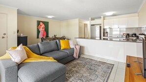 Uma sala de estar moderna com um sofá modular cinza, um tapete estampado e um quadro na parede.