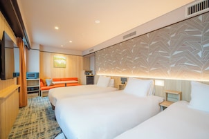 Quarto de hotel com duas camas, um sofá, uma televisão e parede estampada.