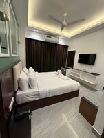 Quarto de hotel moderno com cama, televisão, ventoinha no teto e ar condicionado integrado.