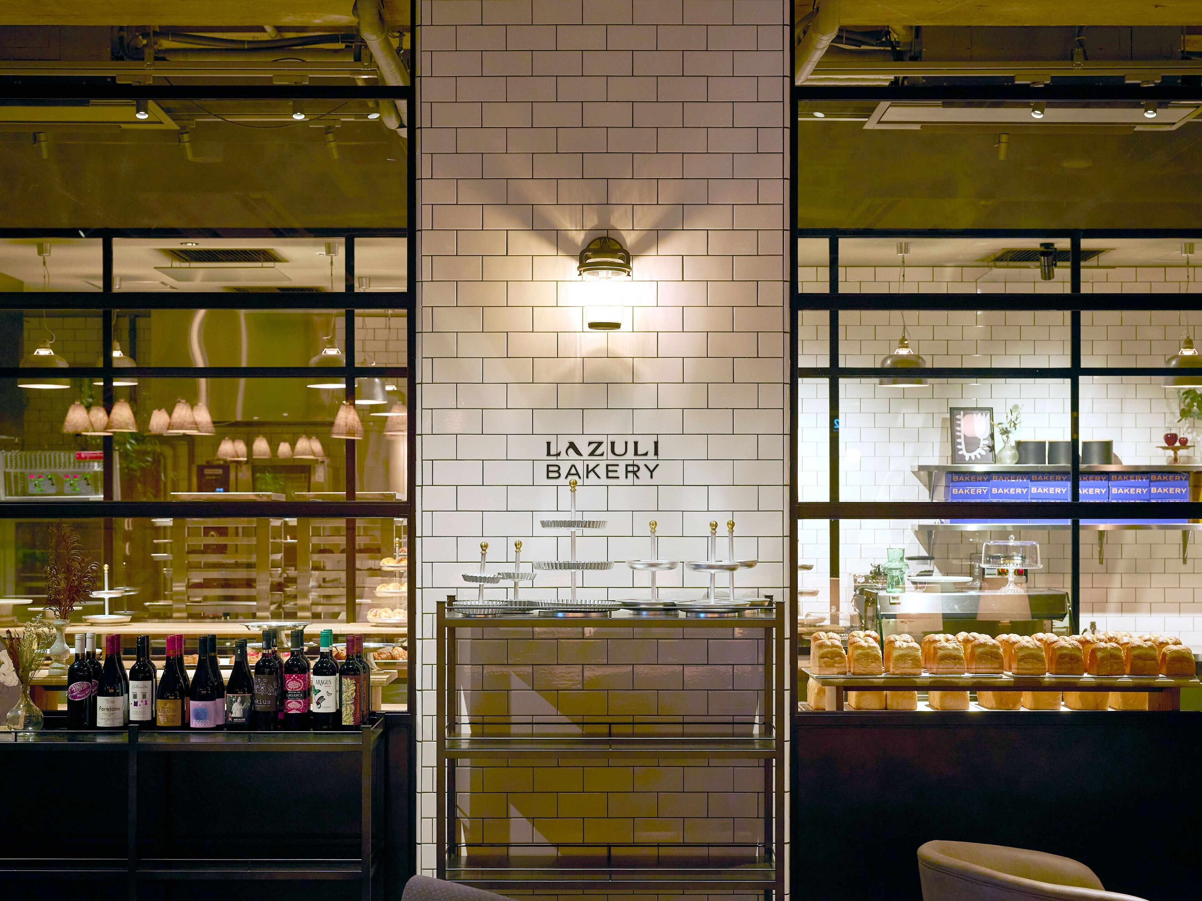 Interior de padaria com parede azulejada, vitrines e balcão com garrafas.
