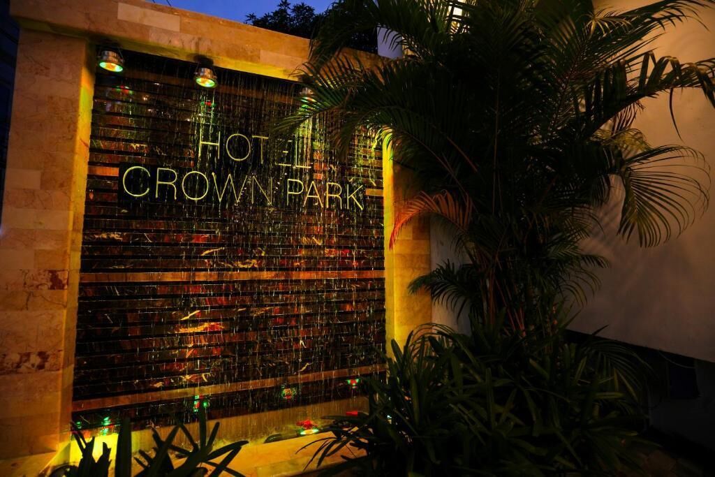 Entrada de hotel com uma placa indicando 'HOTEL CROWN PARK' e uma parede decorativa com linhas verticais.