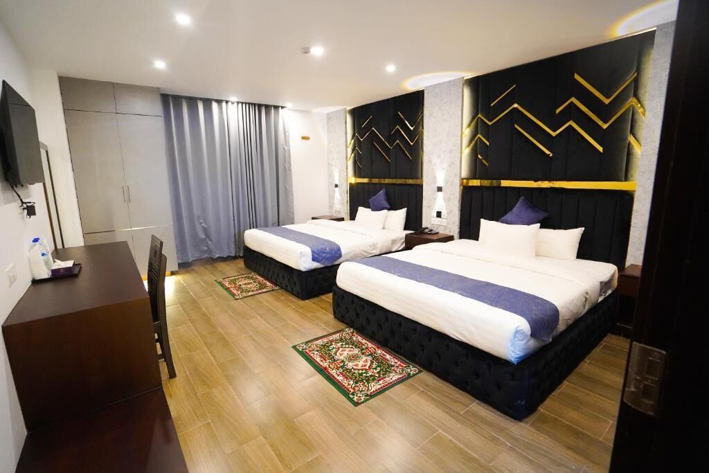 Quarto de hotel com duas camas, uma escrivaninha e uma televisão.
