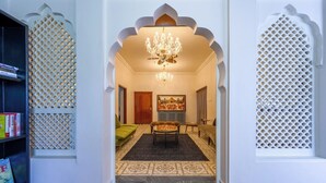 Corredor interior com lustre, piso estampado e decoração tradicional.