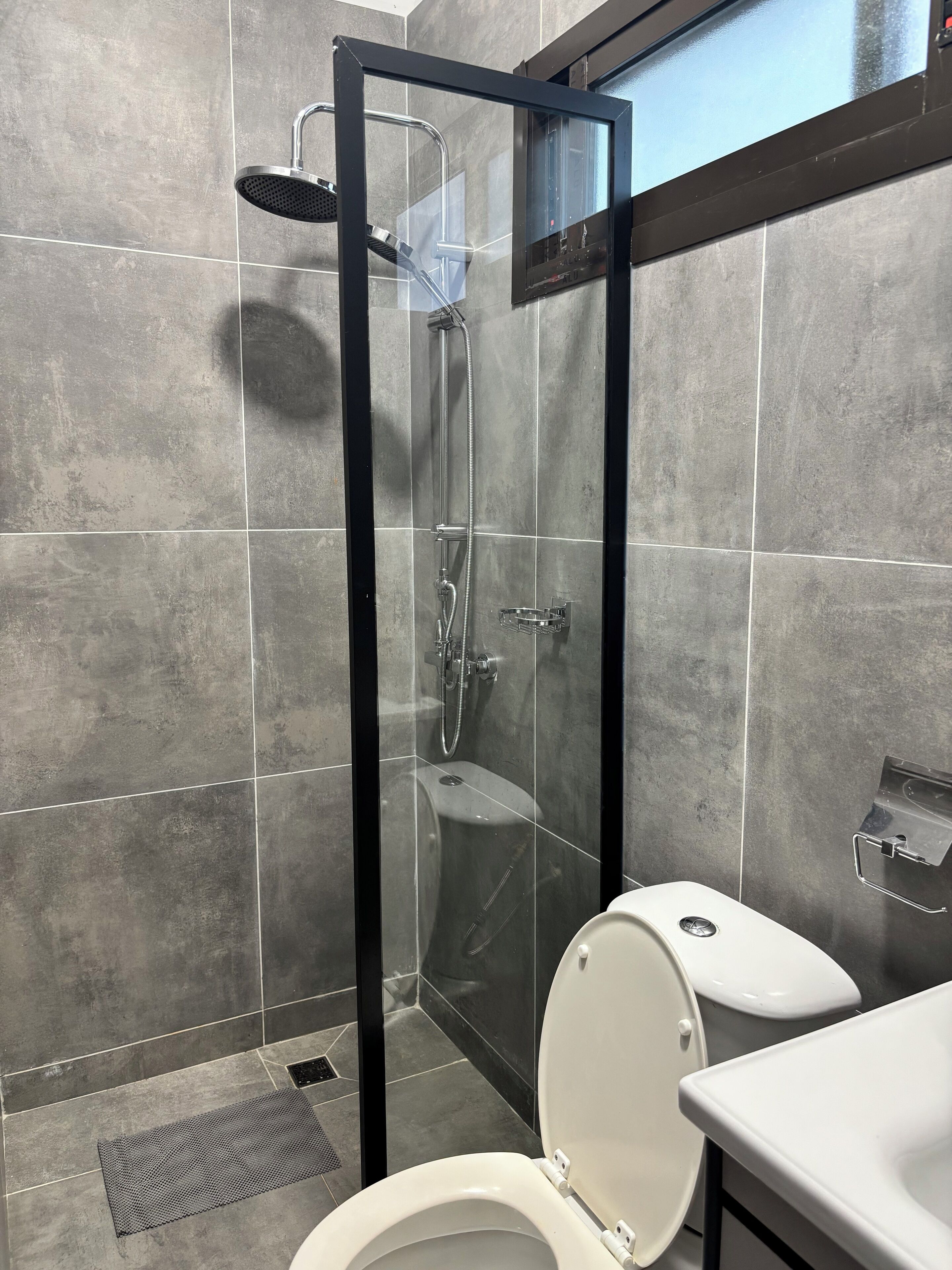 Uma casa de banho moderna com chuveiro em cabine de vidro, sanita e lavatório.