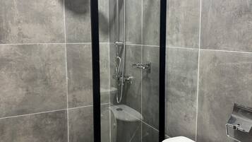 Uma casa de banho moderna com chuveiro em cabine de vidro, sanita e lavatório.