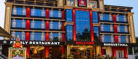 Um hotel com um letreiro de 'Bem-vindo', um 'Restaurante Familiar' e um anúncio de 'Salão de Festas'.