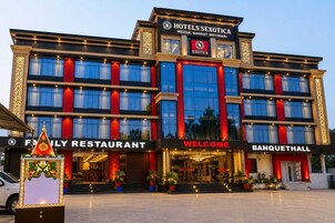 Um hotel com um letreiro de 'Bem-vindo', um 'Restaurante Familiar' e um anúncio de 'Salão de Festas'.
