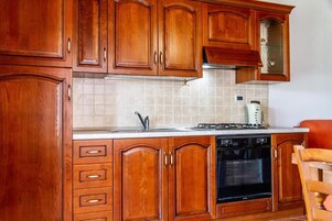 Um frigorífico, um forno, uma placa de cozinha, utensílios de cozinha 