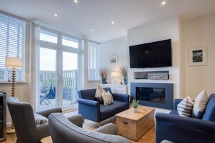 Uma sala de estar moderna com lareira, televisão de tela plana e vista para o exterior.