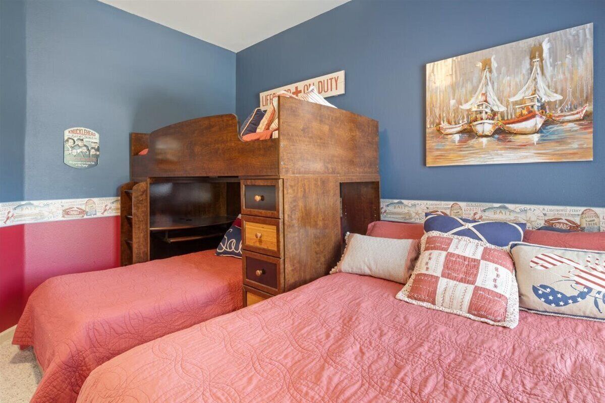 Quarto com duas camas, incluindo uma beliche de madeira, uma televisão e um quadro com tema náutico.