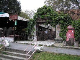 Uma entrada rústica com um portão de madeira, uma placa e uma pequena escadaria que leva a um edifício.