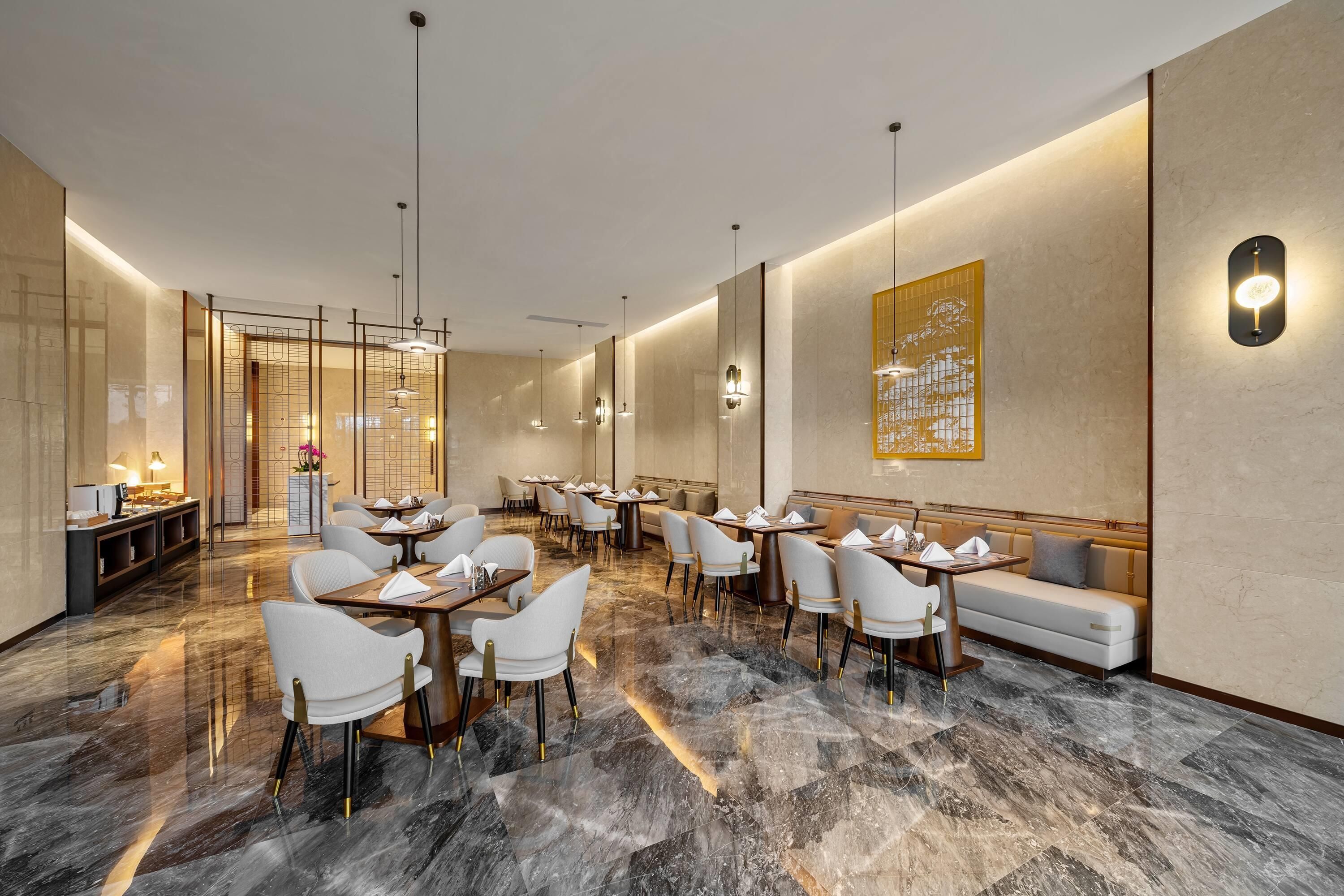 Um hall de hotel moderno com piso de mármore, áreas de estar e luminárias contemporâneas.
