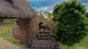 Parede de pedra com um logotipo e o texto "HOTEL EL PARAISO CALAKMUL".