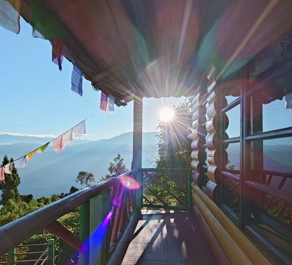Uma cabana de madeira com varanda com vista para uma paisagem montanhosa.