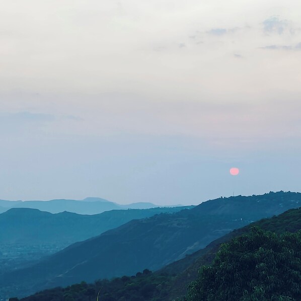 Paisagem com montanhas e o sol se pondo.