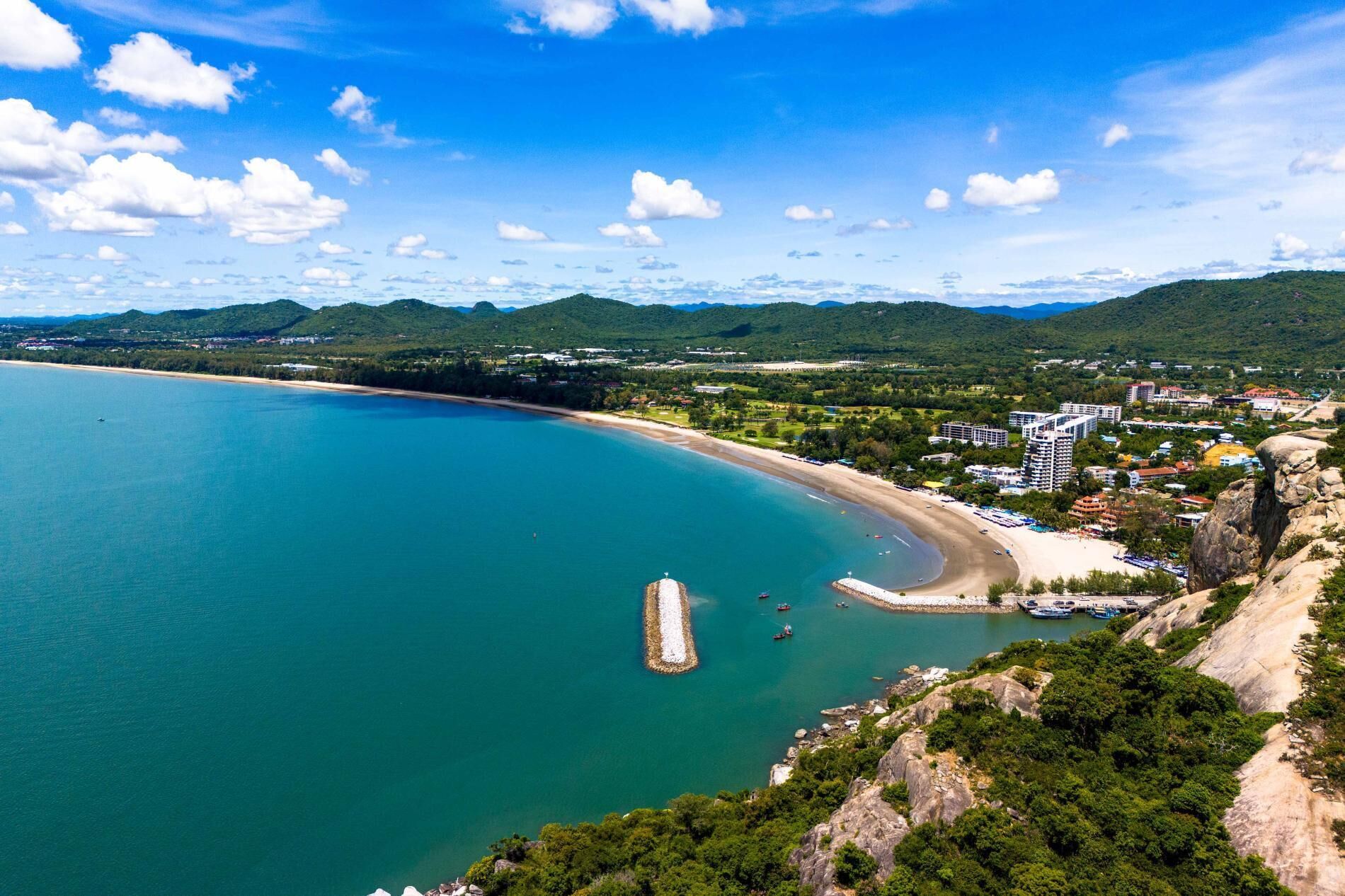 Uma cidade costeira com praia, um cais e edifícios ao fundo.
