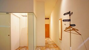 Um corredor com piso estampado, um aparador de casacos e um quadro de avisos, e uma porta que dá para um quarto.