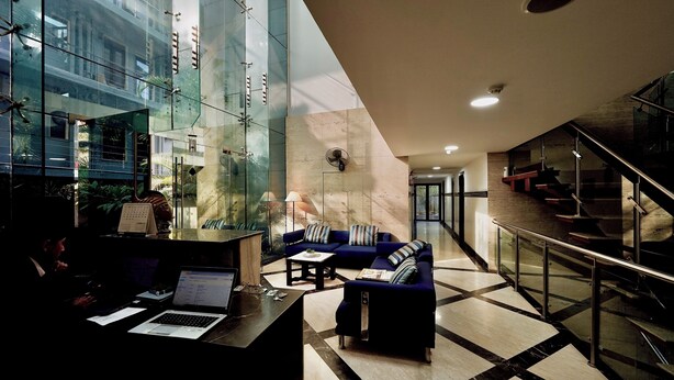 Um lobby moderno com balcão de recepção, área de estar e escadaria.