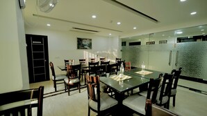 Uma sala de jantar moderna com uma mesa grande e cadeiras, um quadro na parede e um painel de vidro fosco.