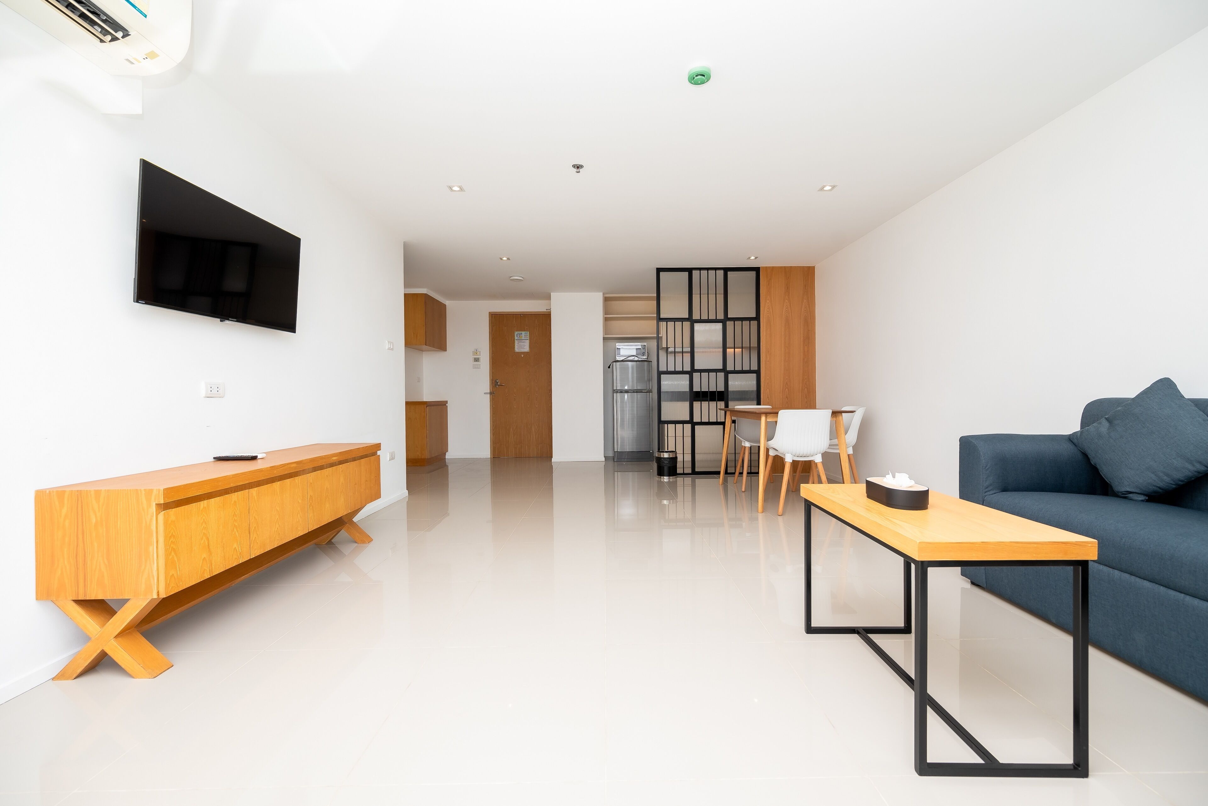 Uma sala de estar moderna com um console de madeira, um sofá azul e uma pequena mesa de madeira com cadeiras.