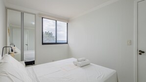 Quarto com cama, janela com vista, espelho e porta.