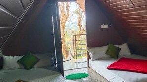 Quarto com duas camas, teto de madeira e vista para árvores.