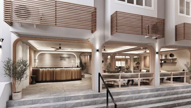 Um hall de hotel moderno com balcão de recepção, área de estar e escadaria para os andares superiores.