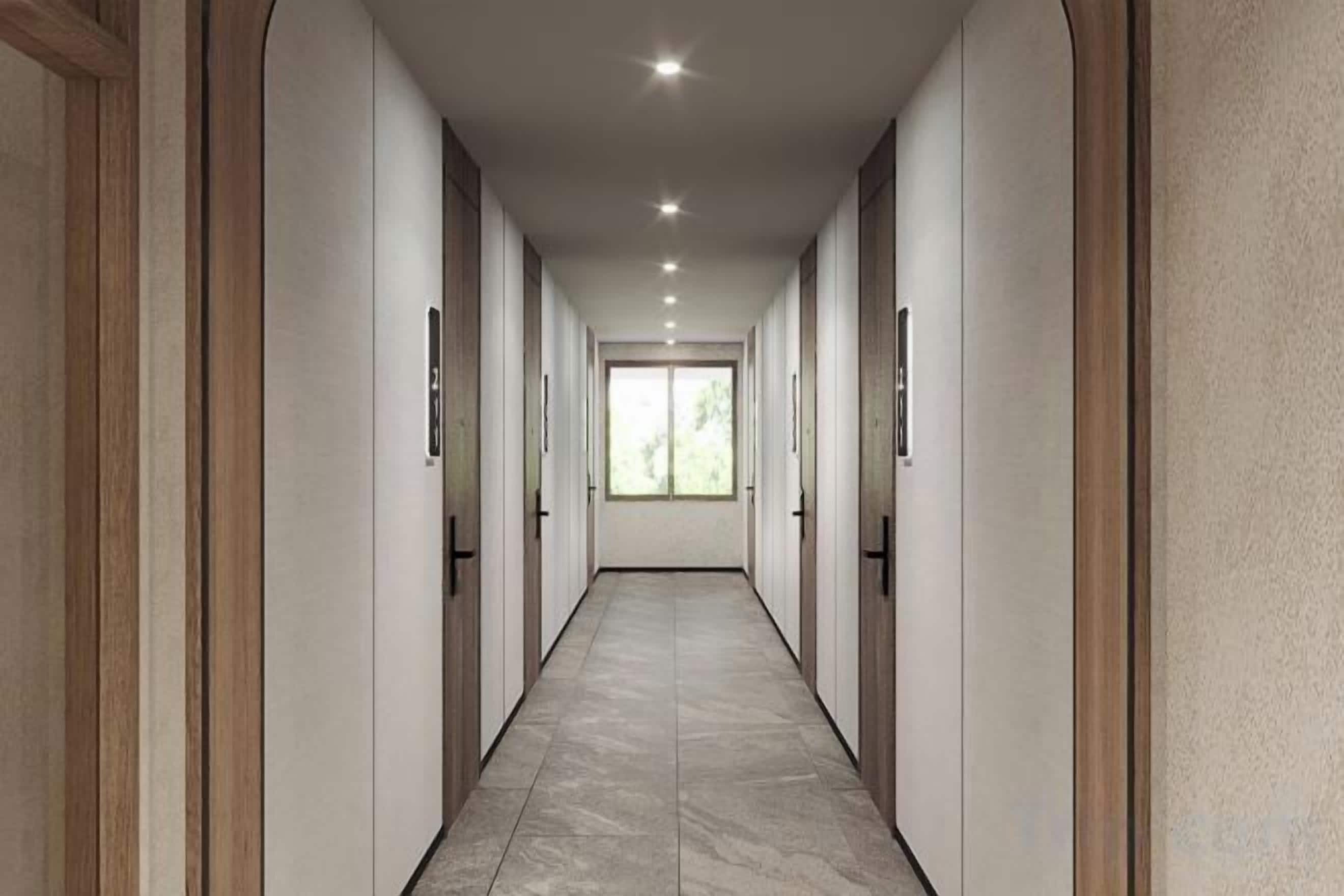 Corredor com portas em ambos os lados, iluminação embutida e vista para o exterior.