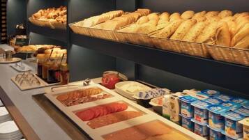 Buffet com diversos alimentos, incluindo pães, carnes e laticínios.
