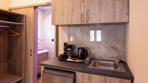 Cozinha compacta com armários de madeira, pia de aço inoxidável e cafeteira.