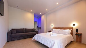 Um quarto com uma cama, um sofá e uma mesa de cabeceira com abajur.