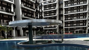 Um edifício moderno com uma piscina circular rodeada por um deck ladrilhado.