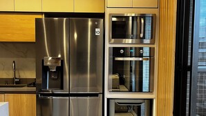 Uma cozinha moderna com eletrodomésticos de aço inoxidável, incluindo geladeira, micro-ondas e forno.