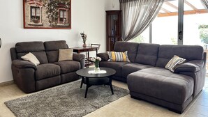 Uma sala de estar com dois sofás, uma mesa de centro, um quadro e uma janela com cortinas.