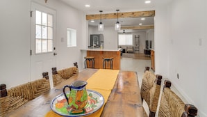 Uma cozinha moderna com uma ilha central, cadeiras de madeira e uma mesa de jantar com um jarro colorido.