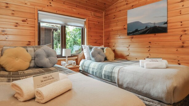 Um quarto de cabana aconchegante, com duas camas, uma janela grande e um quadro na parede.