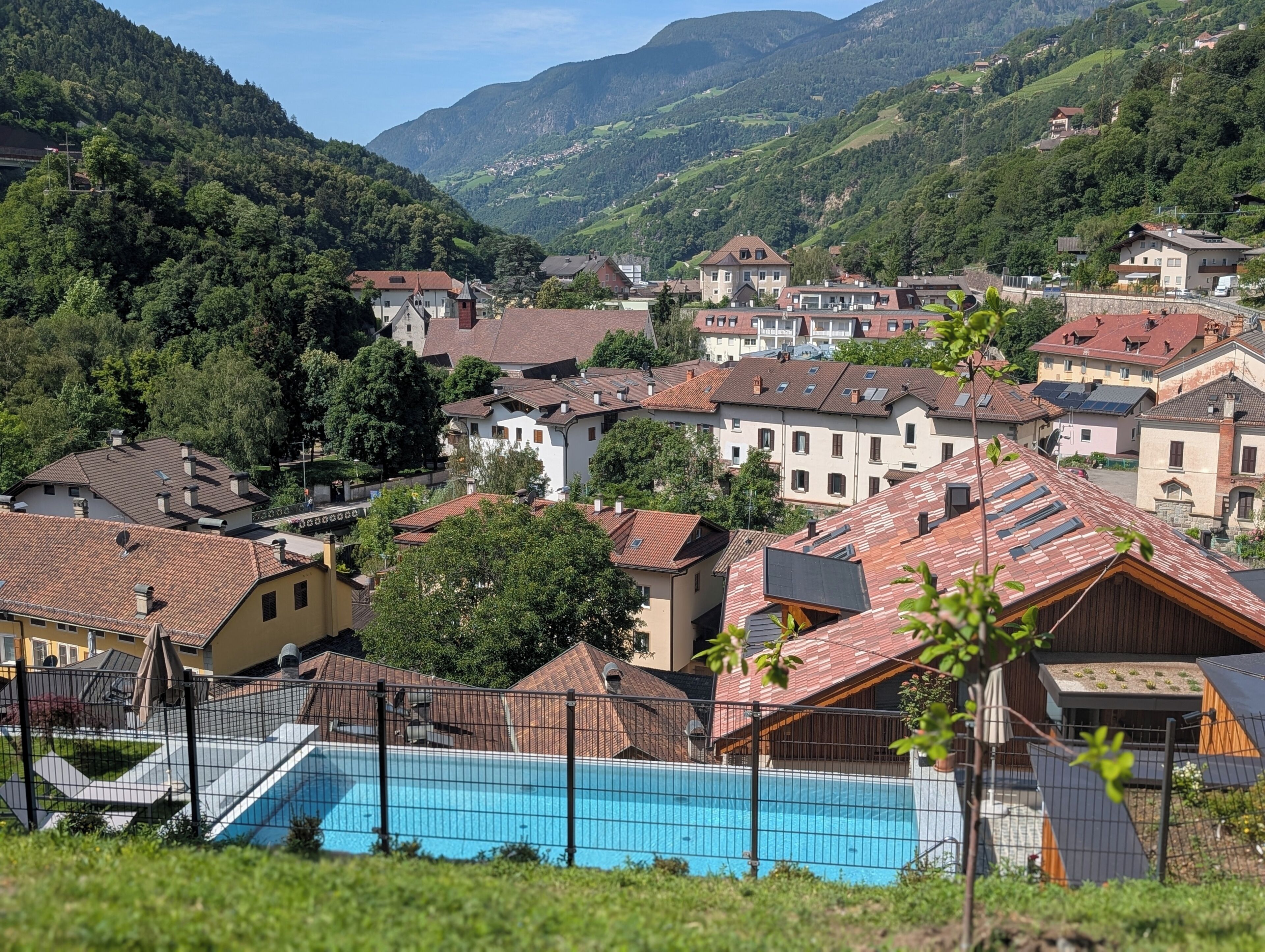 Zona residencial com casas, piscina e montanhas ao fundo.