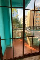 Uma varanda com vista para a paisagem urbana, incluindo edifícios e uma palmeira.