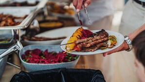 Buffet com diversos pratos, incluindo carnes grelhadas e legumes.