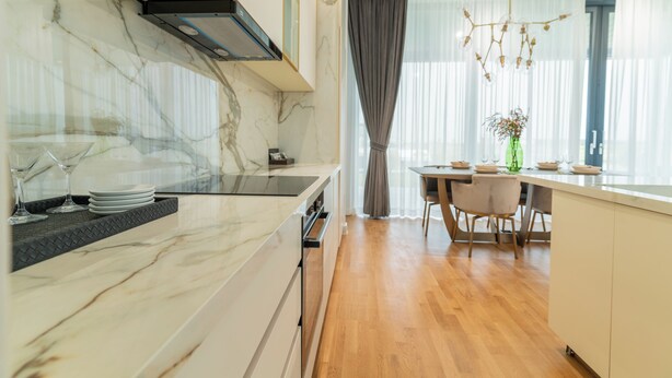 Cozinha moderna com bancadas de mármore, forno embutido e área de jantar com mesa e cadeiras.