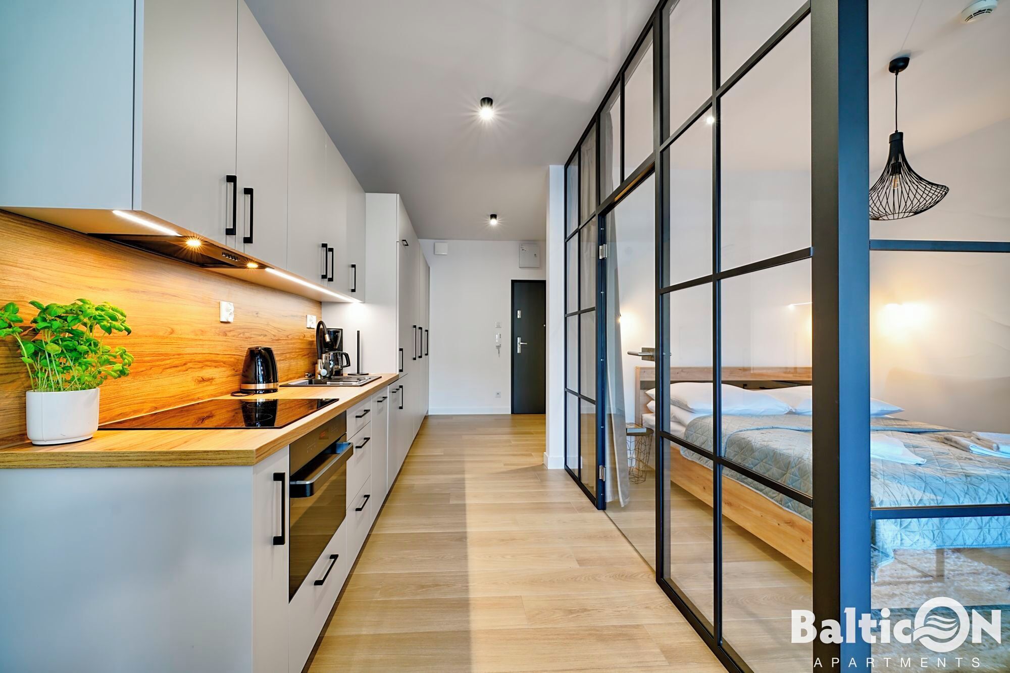 Cozinha moderna com bancada de madeira, cafeteira e planta em vaso.