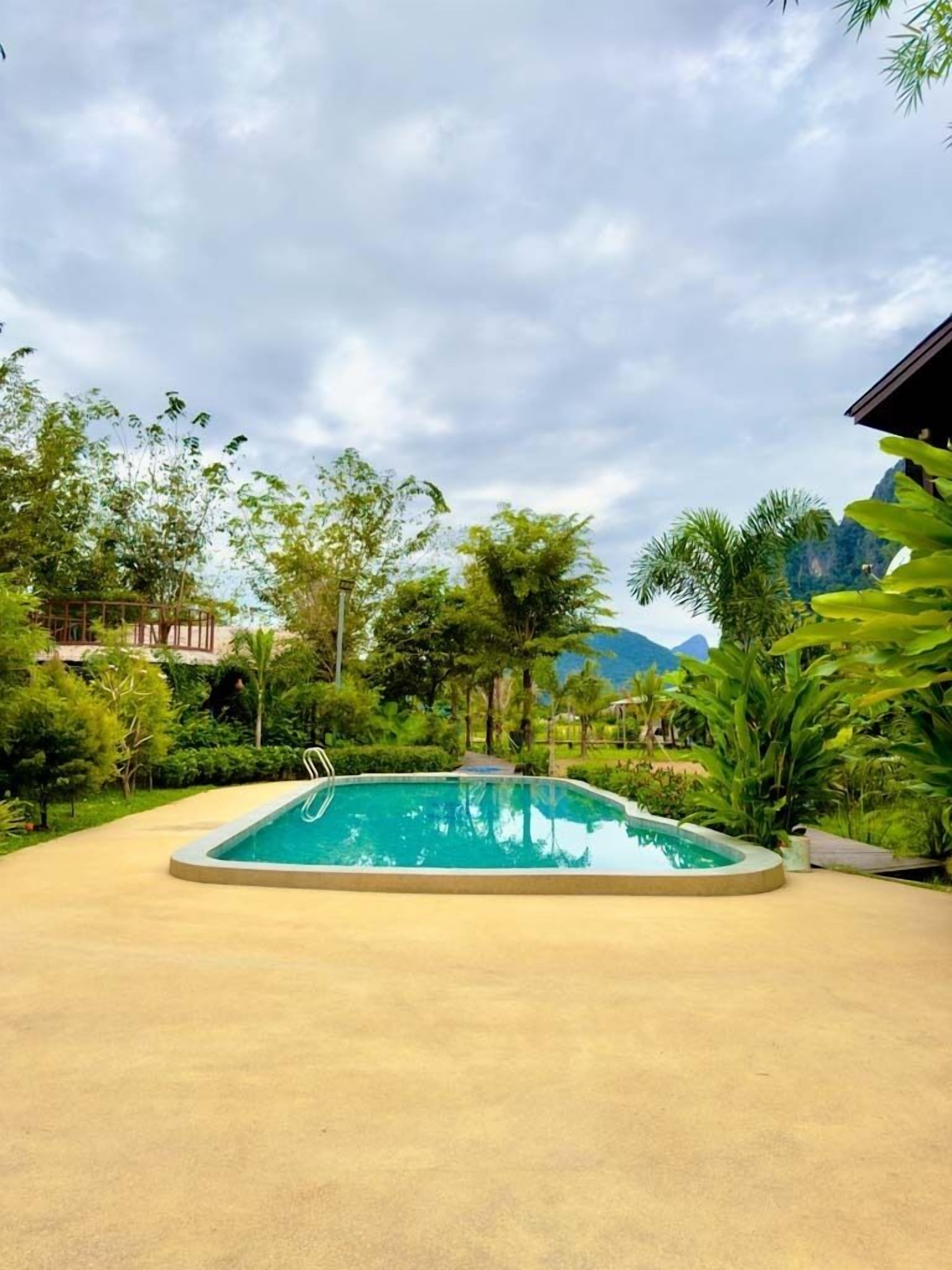 Piscina rodeada por vegetação exuberante e montanhas ao fundo.