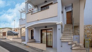 Um edifício residencial com várias andares, varandas, escadaria e garagem.