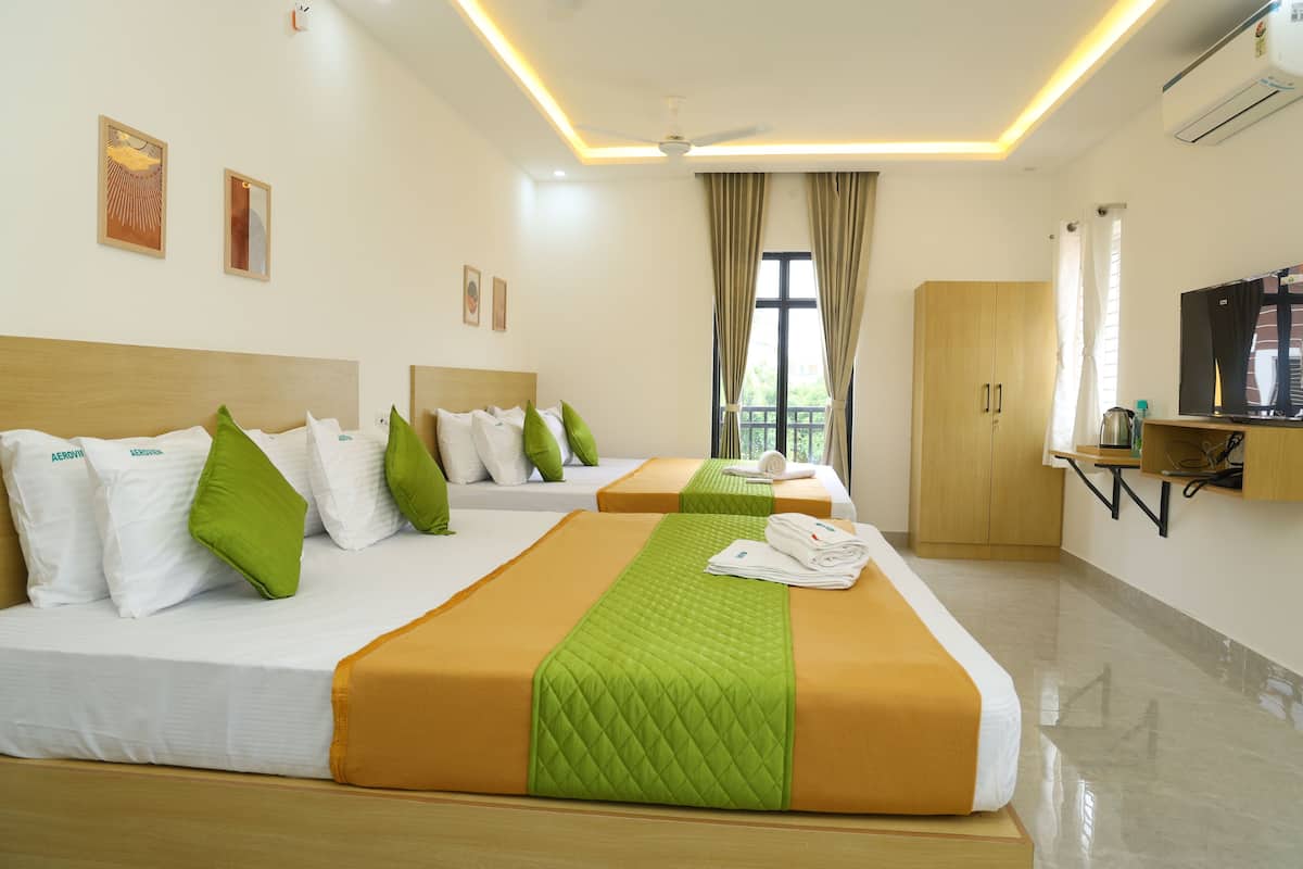 Quarto de hotel com duas camas, um guarda-roupa, uma televisão e um ventilador de teto.