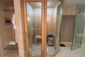 Uma sauna de madeira com portas de vidro, um pequeno banco de madeira e um box de chuveiro envidraçado.