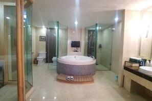 Uma casa de banho moderna com chuveiro em cabine de vidro, uma banheira redonda grande e uma área de casa de banho separada.