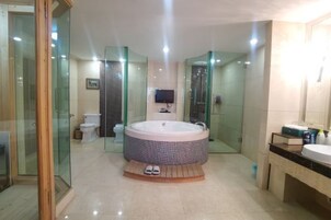 Uma casa de banho moderna com chuveiro em cabine de vidro, uma banheira redonda grande e uma área de casa de banho separada.