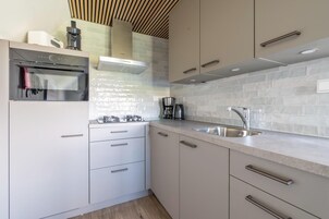 Uma cozinha moderna com armários brancos, pia de aço inoxidável e forno embutido.